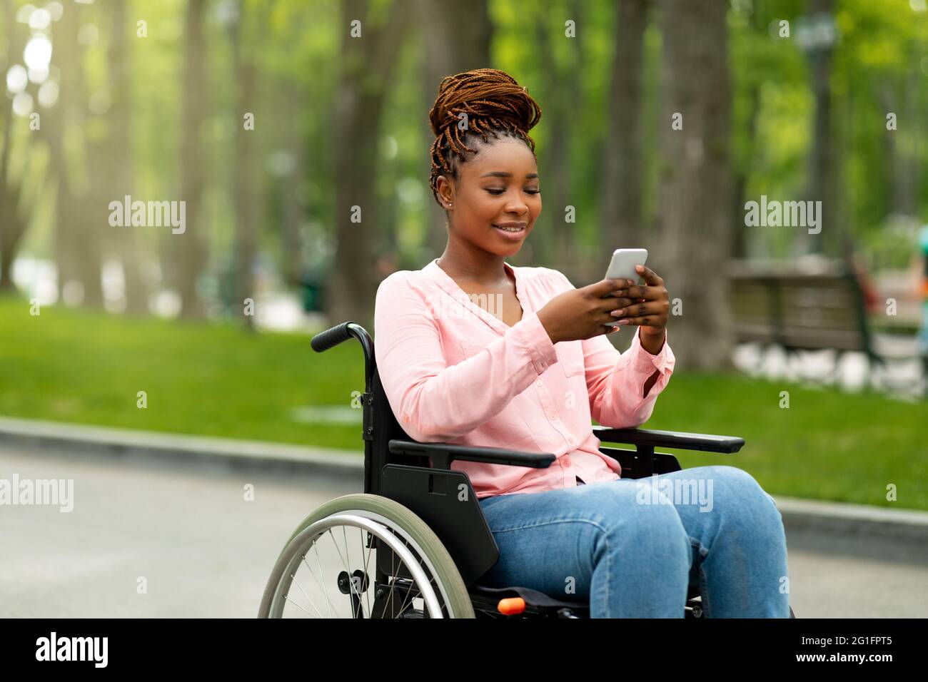 Happy handicapped black woman in wheelchair using smartphone, checking ...