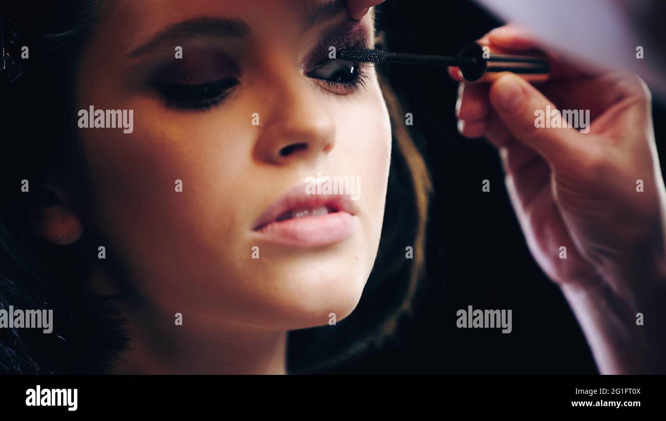 makeup artist applying black mascara on eyelashes of model Stock Photo ...