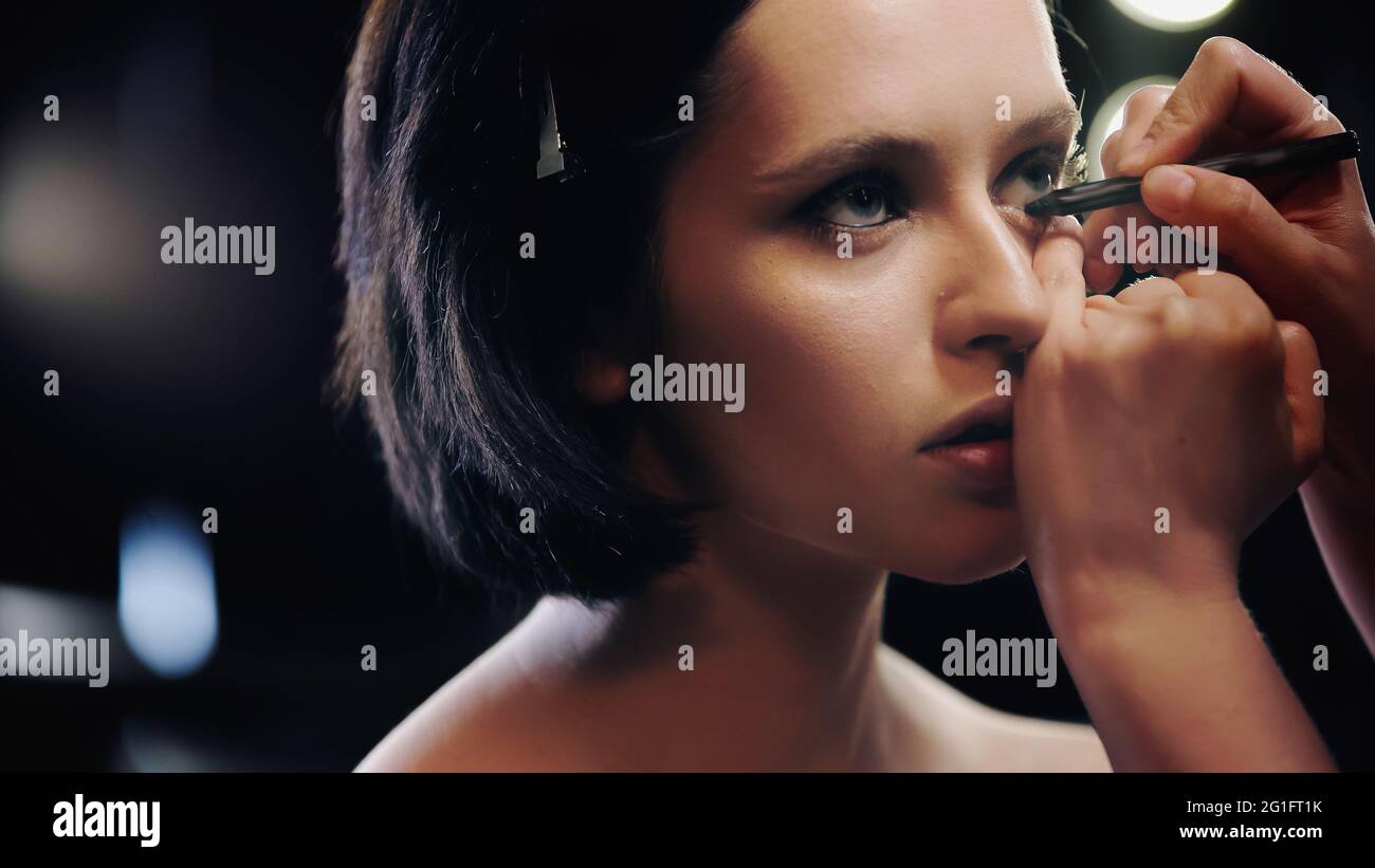 make up artist applying black eyeliner on lower eyelid of model Stock ...