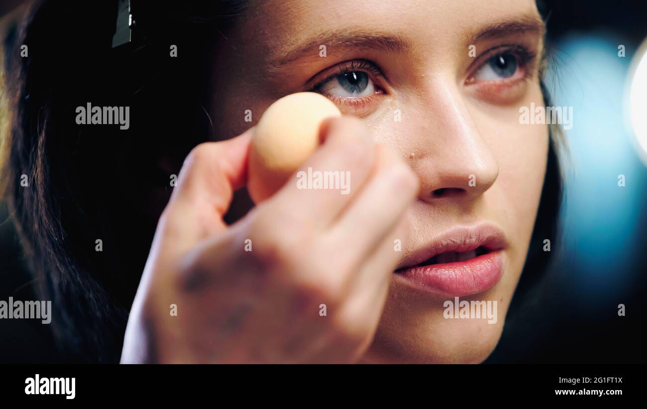 makeup artist applying makeup foundation with cosmetic sponge on face ...