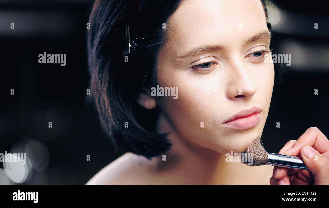 makeup artist applying makeup foundation with cosmetic brush on face of ...