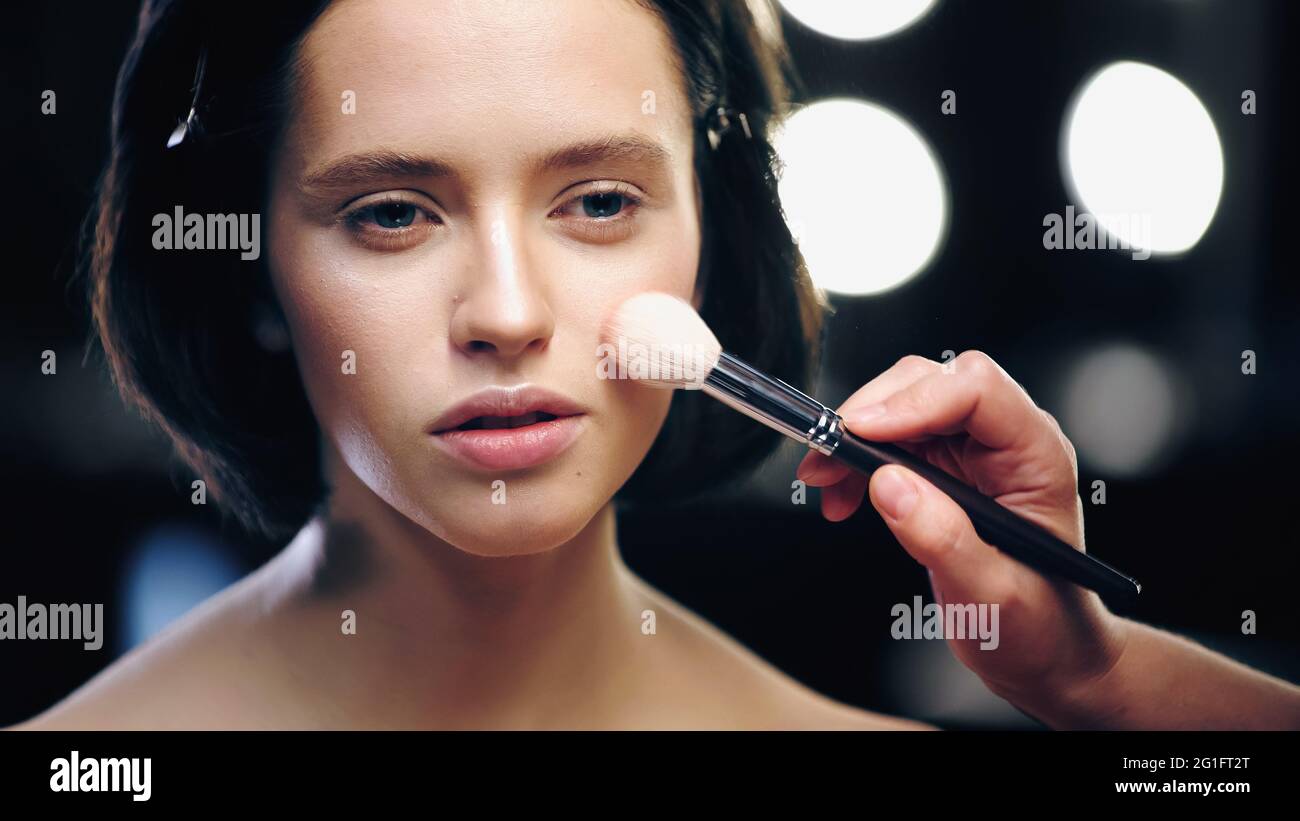 makeup artist applying face foundation with cosmetic brush on skin of ...