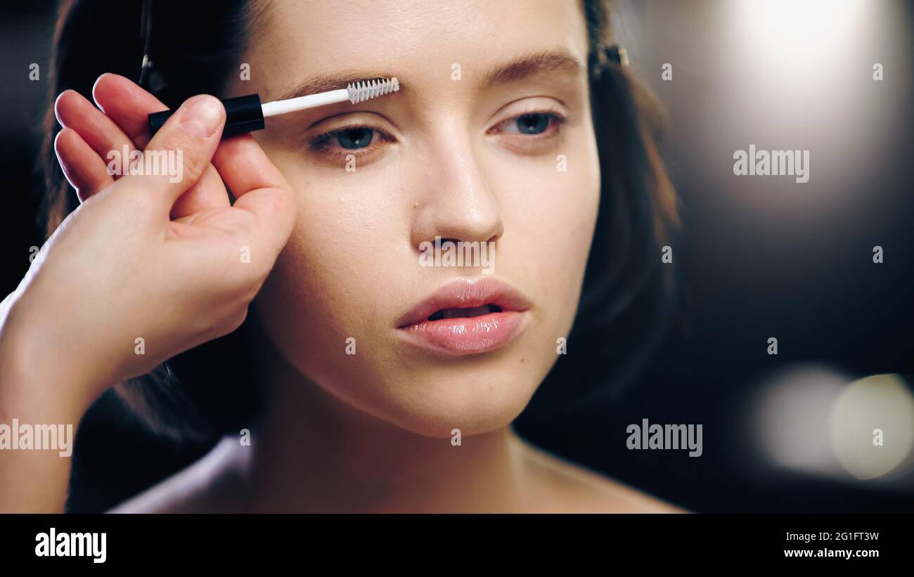 makeup artist brushing eyebrow of young model Stock Photo - Alamy