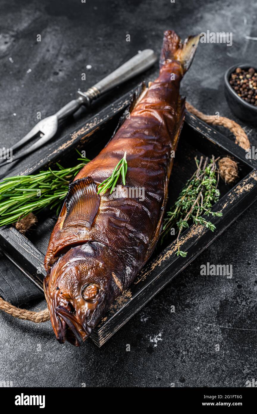 Hot smoked pike perch or zander fish in a wooden tray. Black background ...