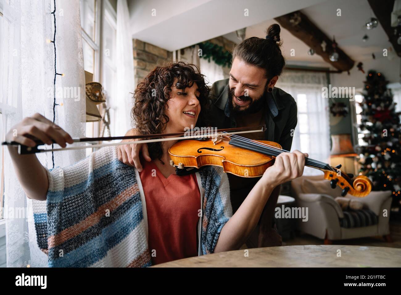 Private male music teacher giving violin lessons to a woman at home ...