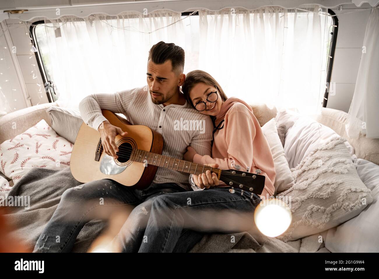 happy woman hugging boyfriend playing guitar in camper Stock Photo - Alamy