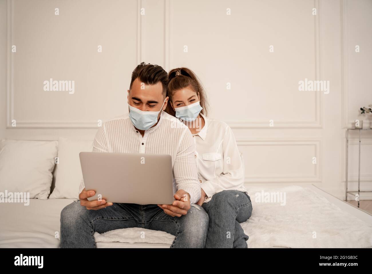 couple in safety masks watching movie on laptop during quarantine at ...