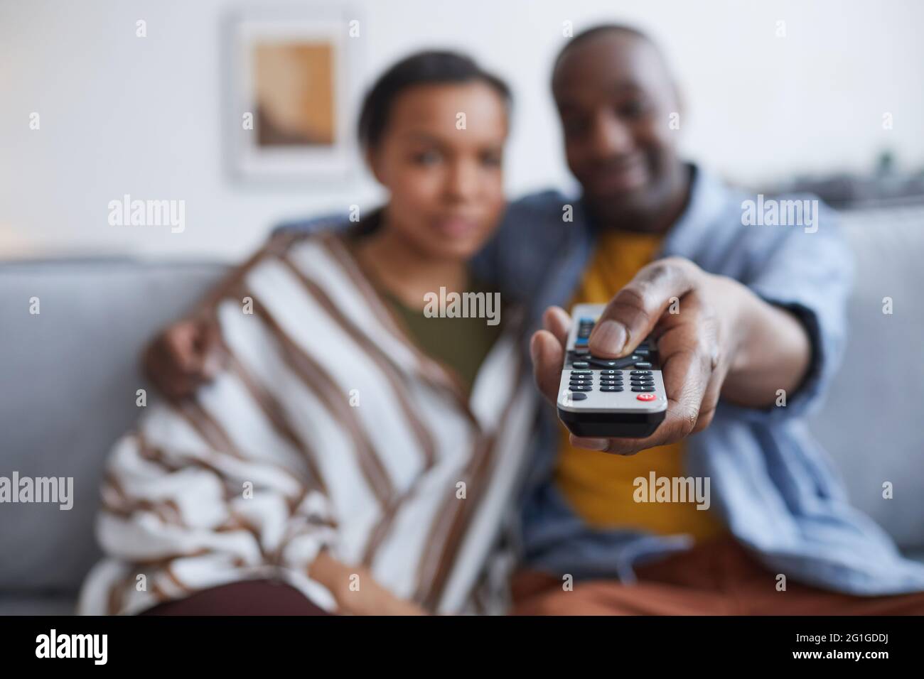 Portrait of young African-American couple watching TV at home together ...