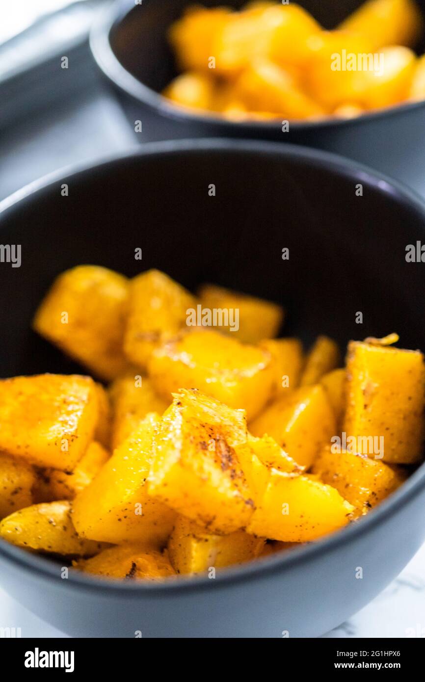 Roasting butternut squash with salt and pepper in olive oil Stock Photo ...