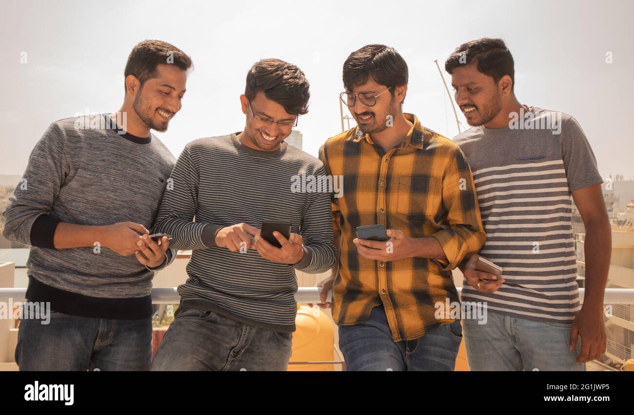 Group of young people watching mobile phone on terrace and laughing ...