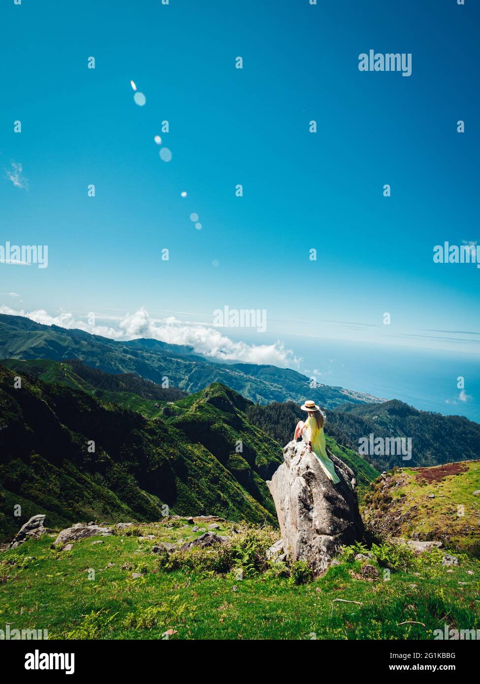 Woman with a summer hat sitting on the rock admitting the stunning ...