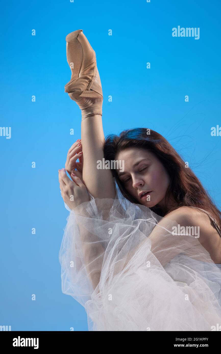 Tired ballet dancer sitting over blue studio background Stock Photo - Alamy