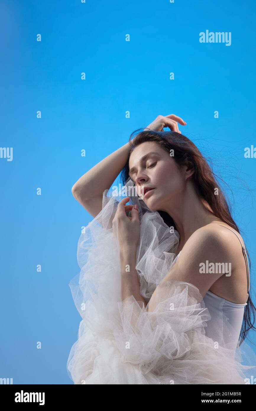 Tired ballet dancer sitting over blue studio background Stock Photo - Alamy