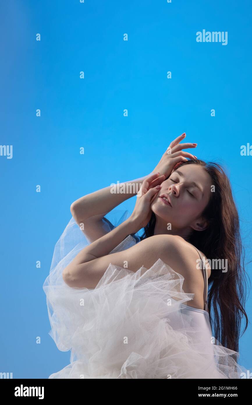 Tired ballet dancer sitting over blue studio background Stock Photo - Alamy
