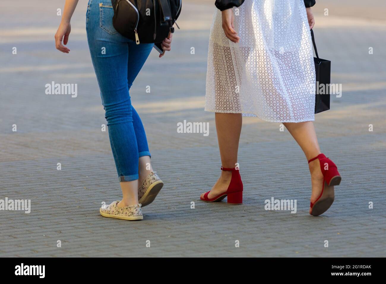 Girls' feet walk around the city in different shoes. One in trousers ...