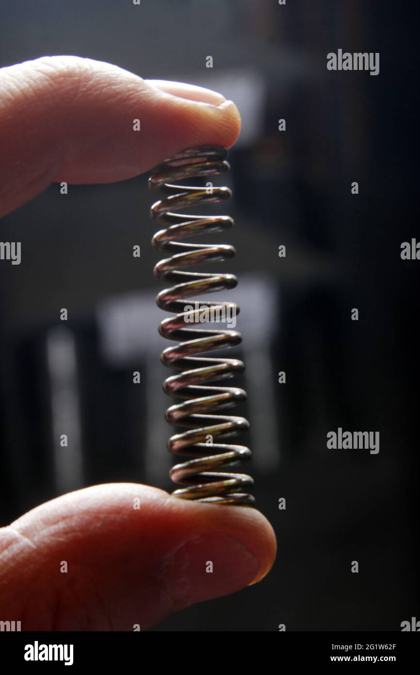 The male hand squeezes a metal spring on a black background Stock Photo ...