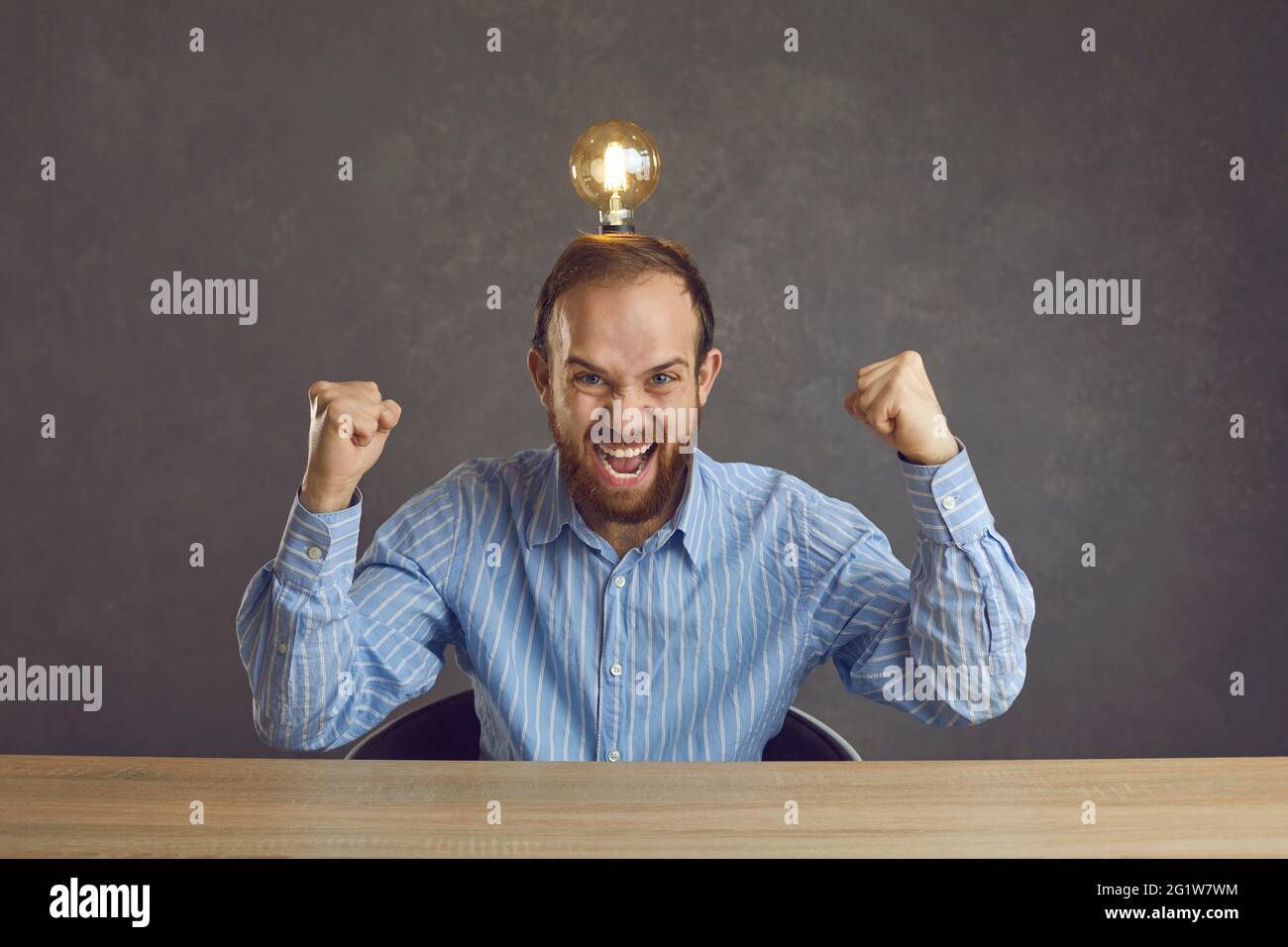 Funny crazy man with idea light bulb on head sitting at desk and ...
