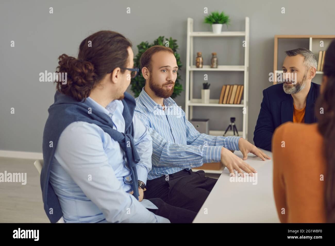 Young company manager or business mentor talking to diverse workers in ...