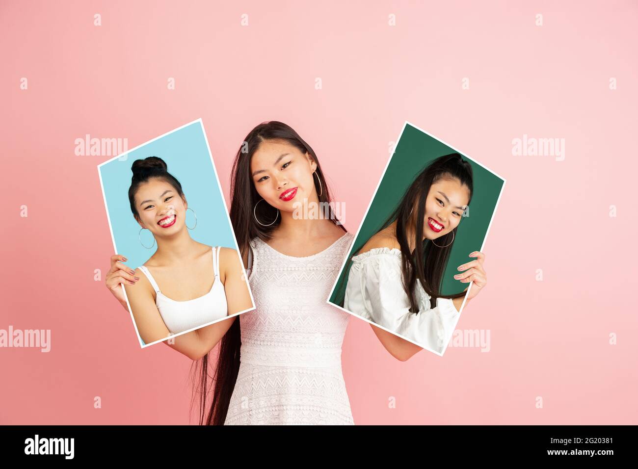 Young girl holding her portraits isolated over studio background with ...