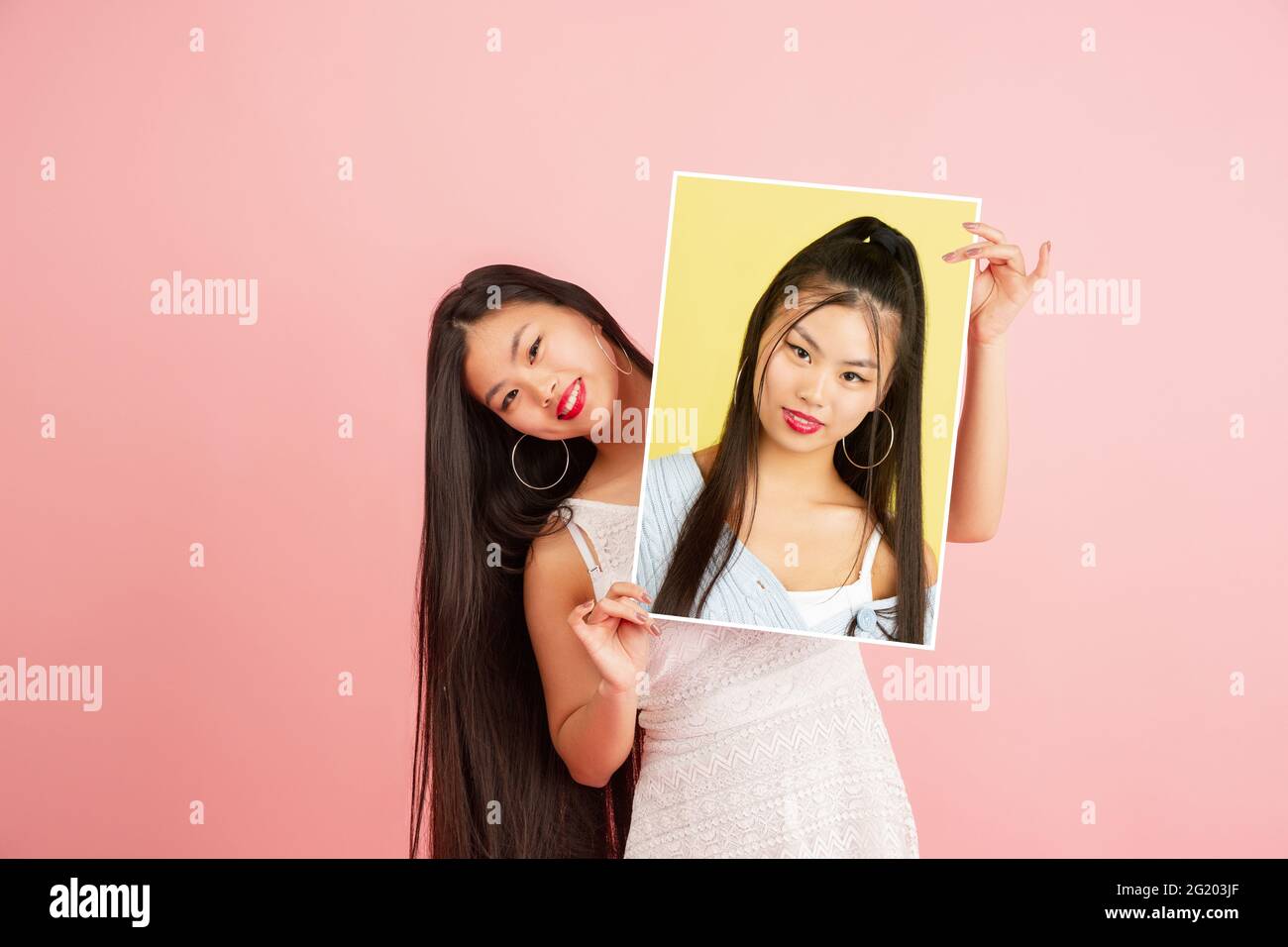 Young girl holding her portrait isolated over studio background with ...