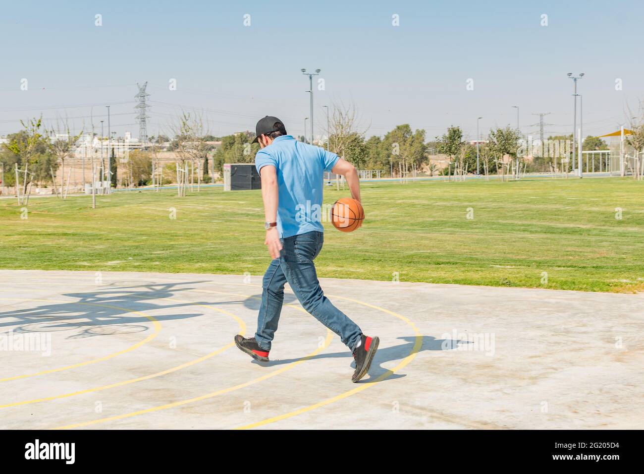 Back view of a Caucasian male playing basketball outdoors, in a public ...