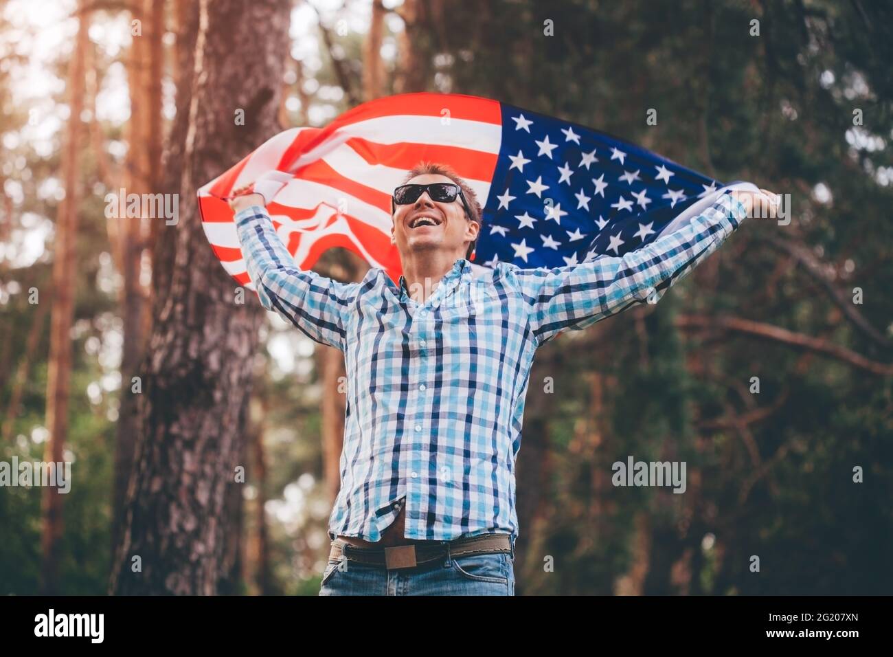 Happy man running with USA flag in park at sunset. Celebrating ...