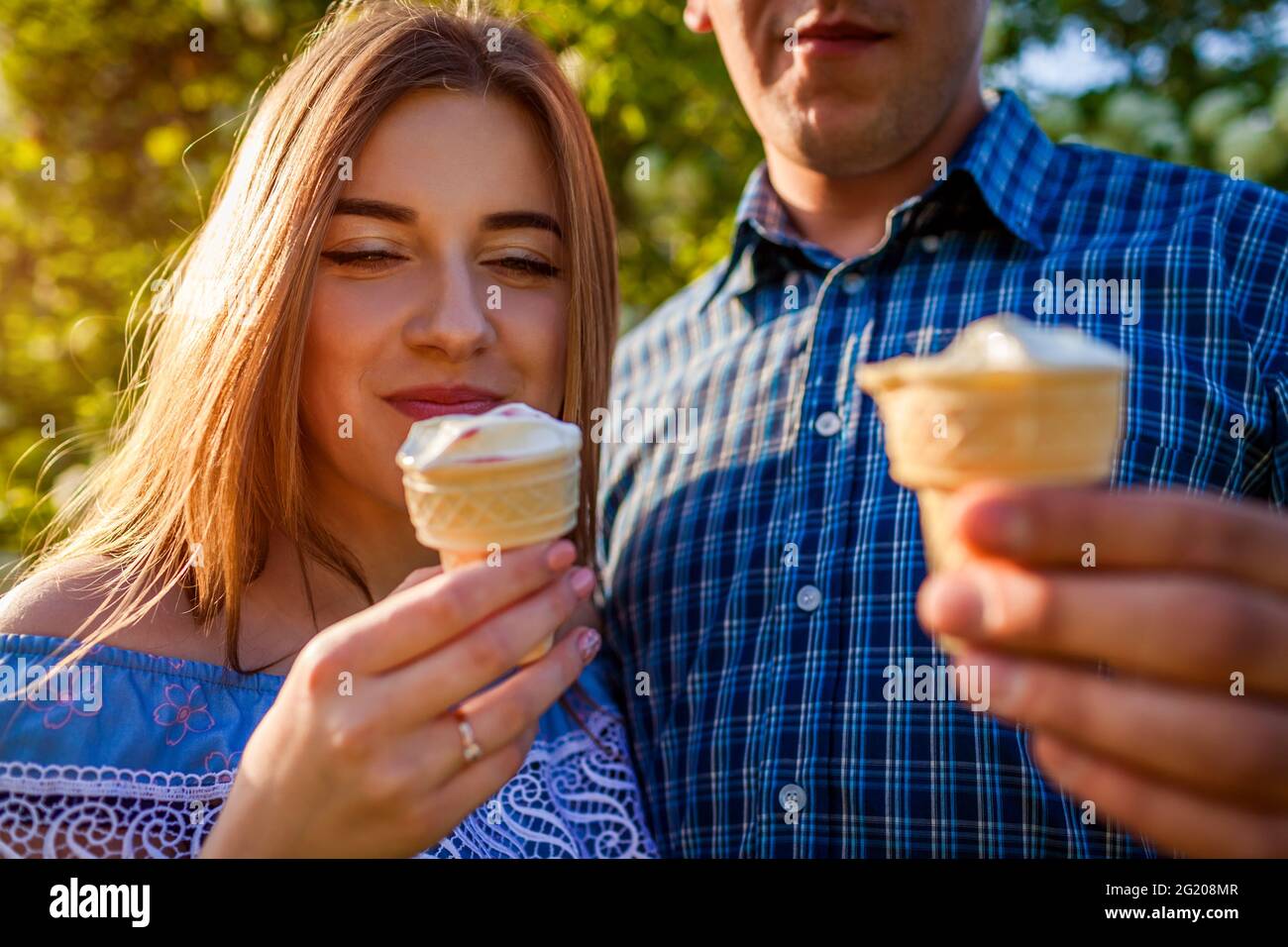 Happy young couple eating ice-cream and chatting outside. Woman and man ...