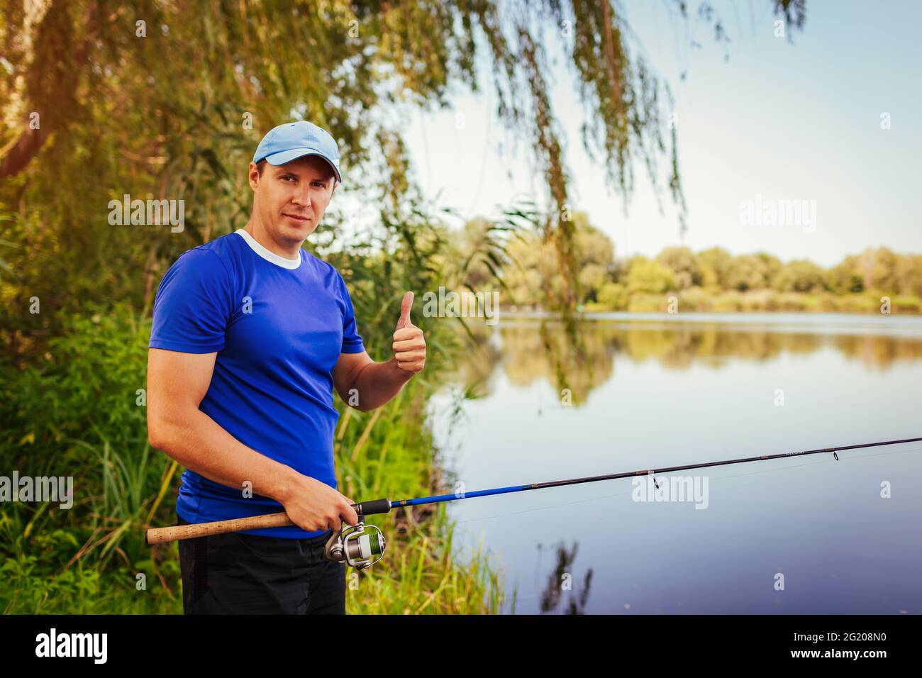 Young man fishing on river. Happy fiserman showing thumb up. Hobby ...