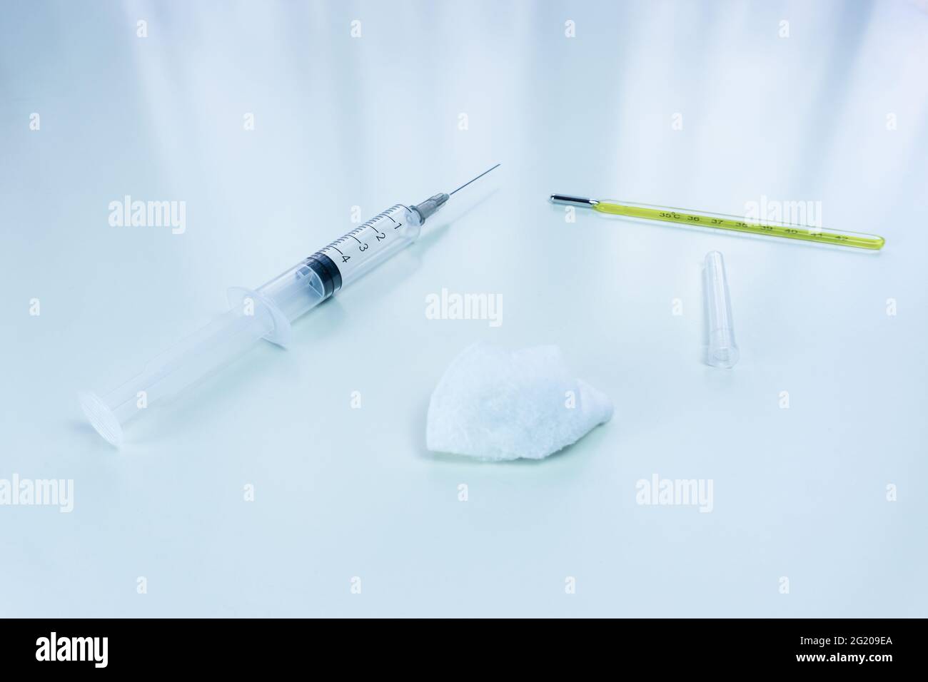 Closeup shot of a thermometer a syringe, and a cotton ball at a ...