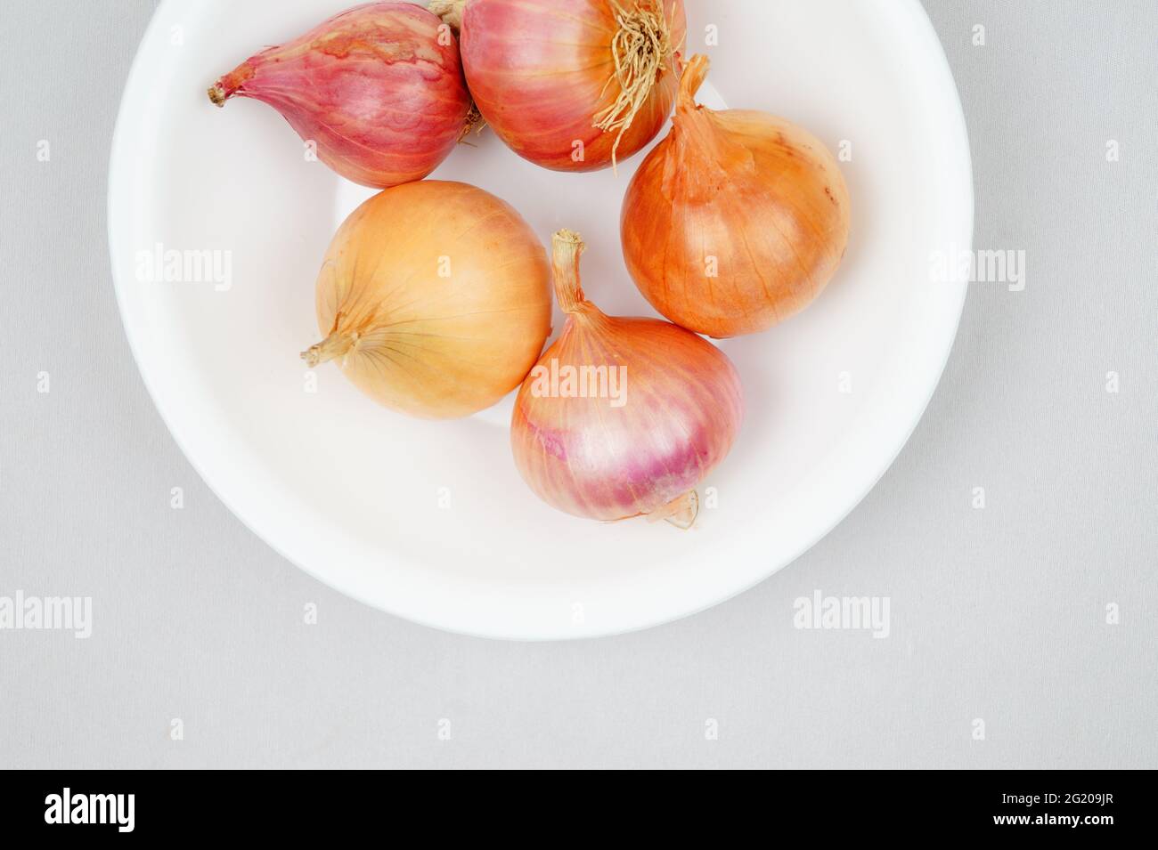 Closeup shot of fresh onions on a plate isolated on a white background ...