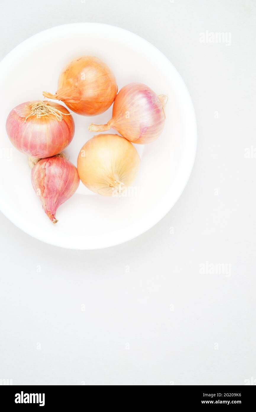 Closeup shot of fresh onions on a plate isolated on a white background ...