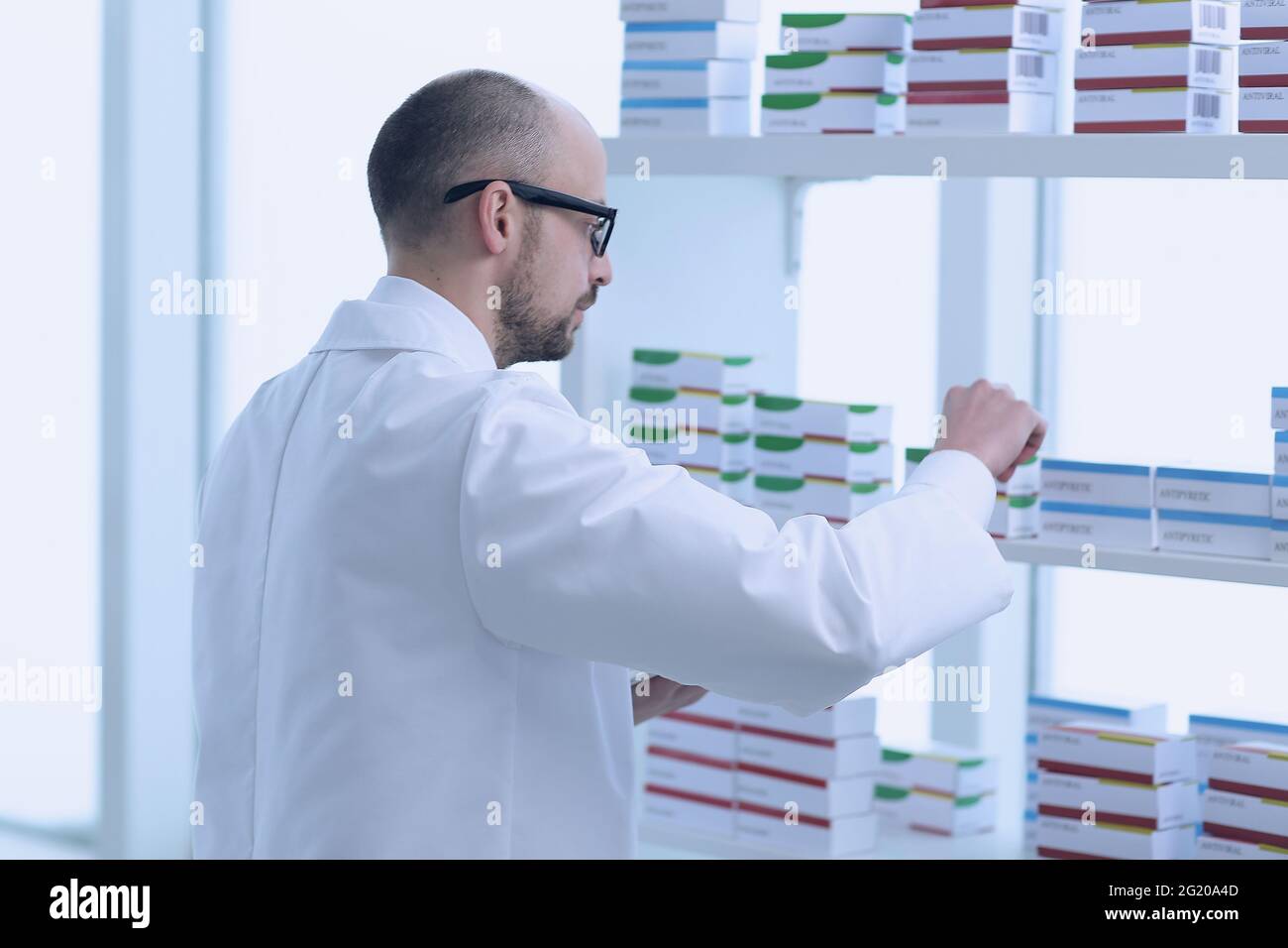 Pharmacist is working. Man wearing special uniform located in pharmacy ...