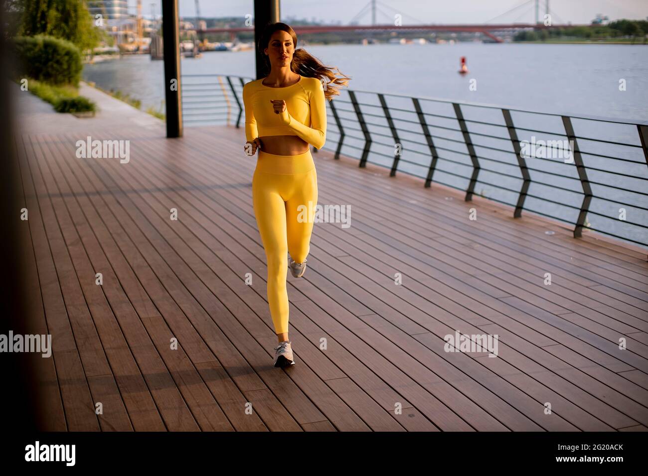 Pretty young woman taking running exercise by the river promenade Stock ...