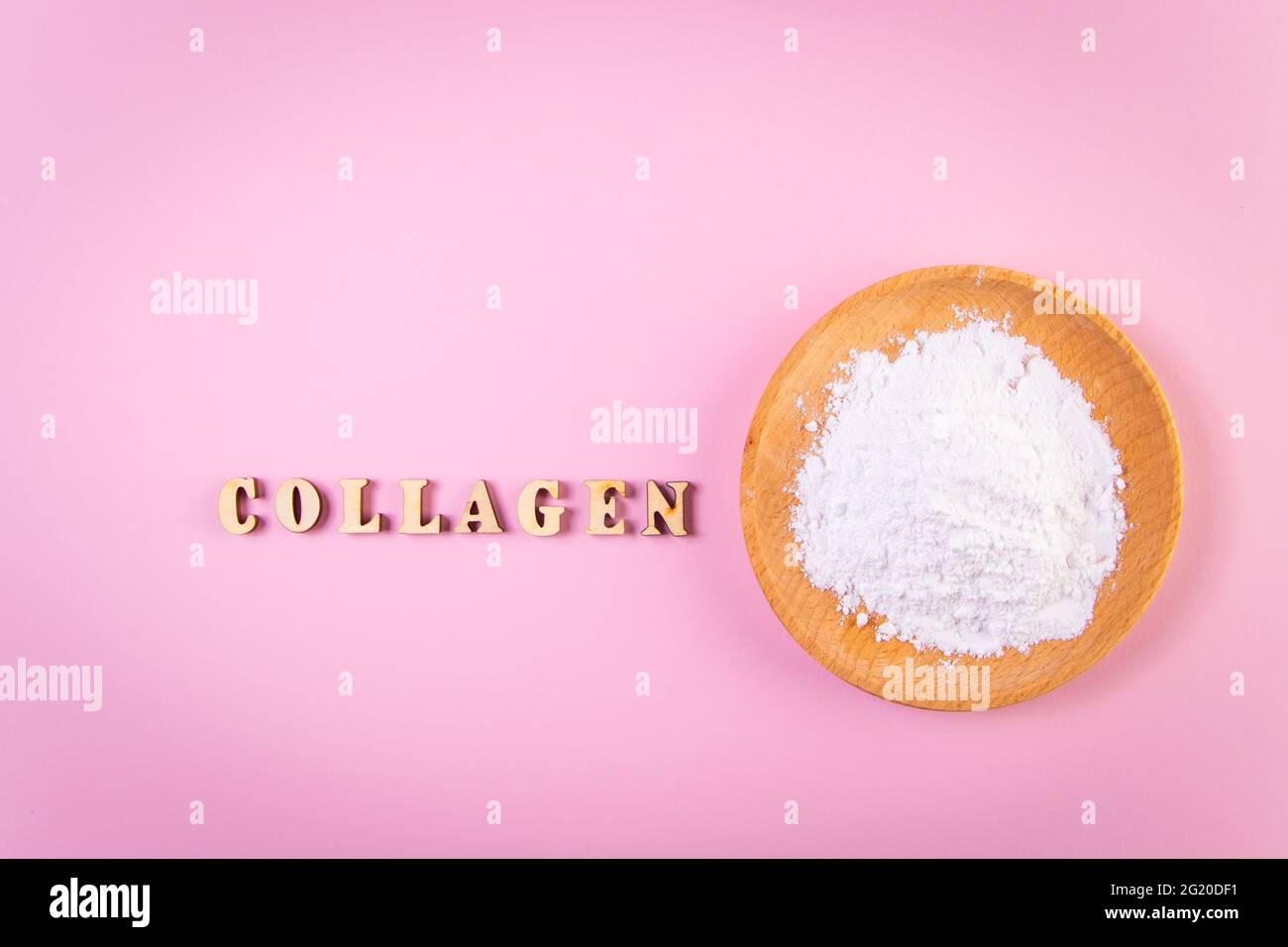 Collagen powder in wooden bowl on pink background. Natural bio ...