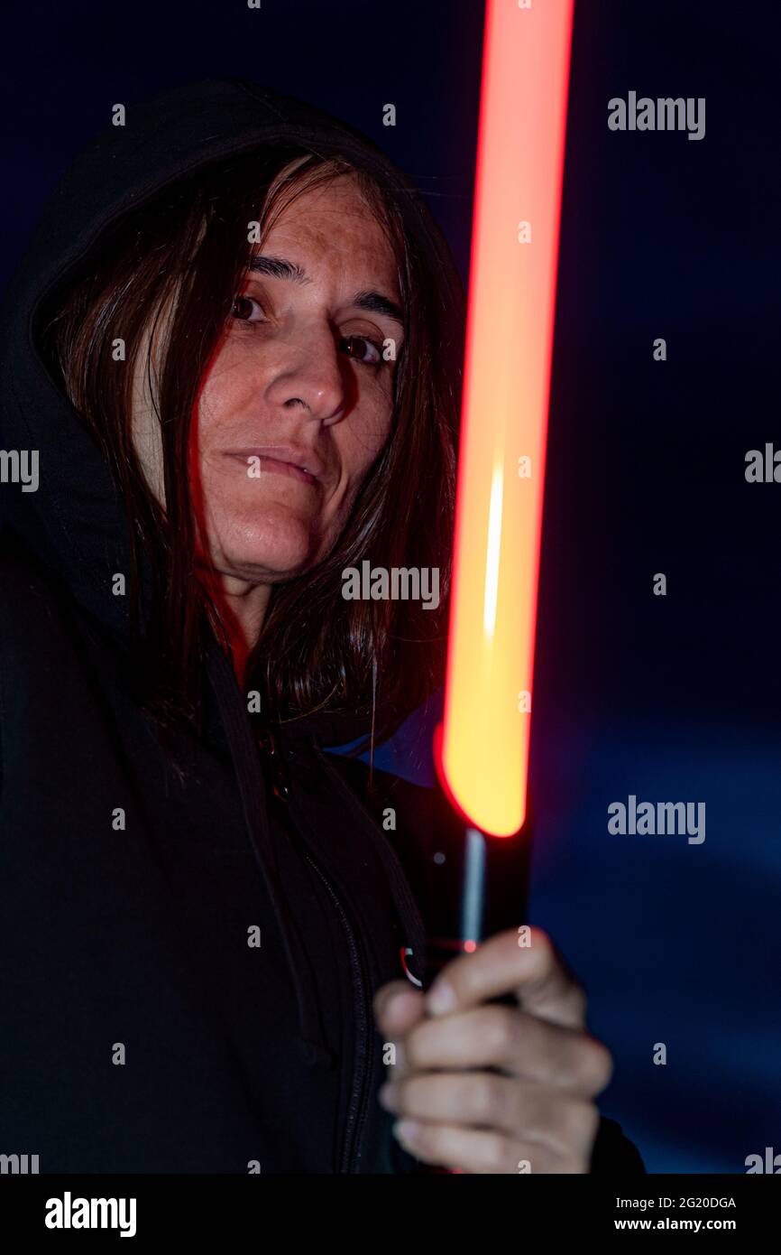 Middle-aged woman holding a LED lightsaber; the concept of cosmic ...