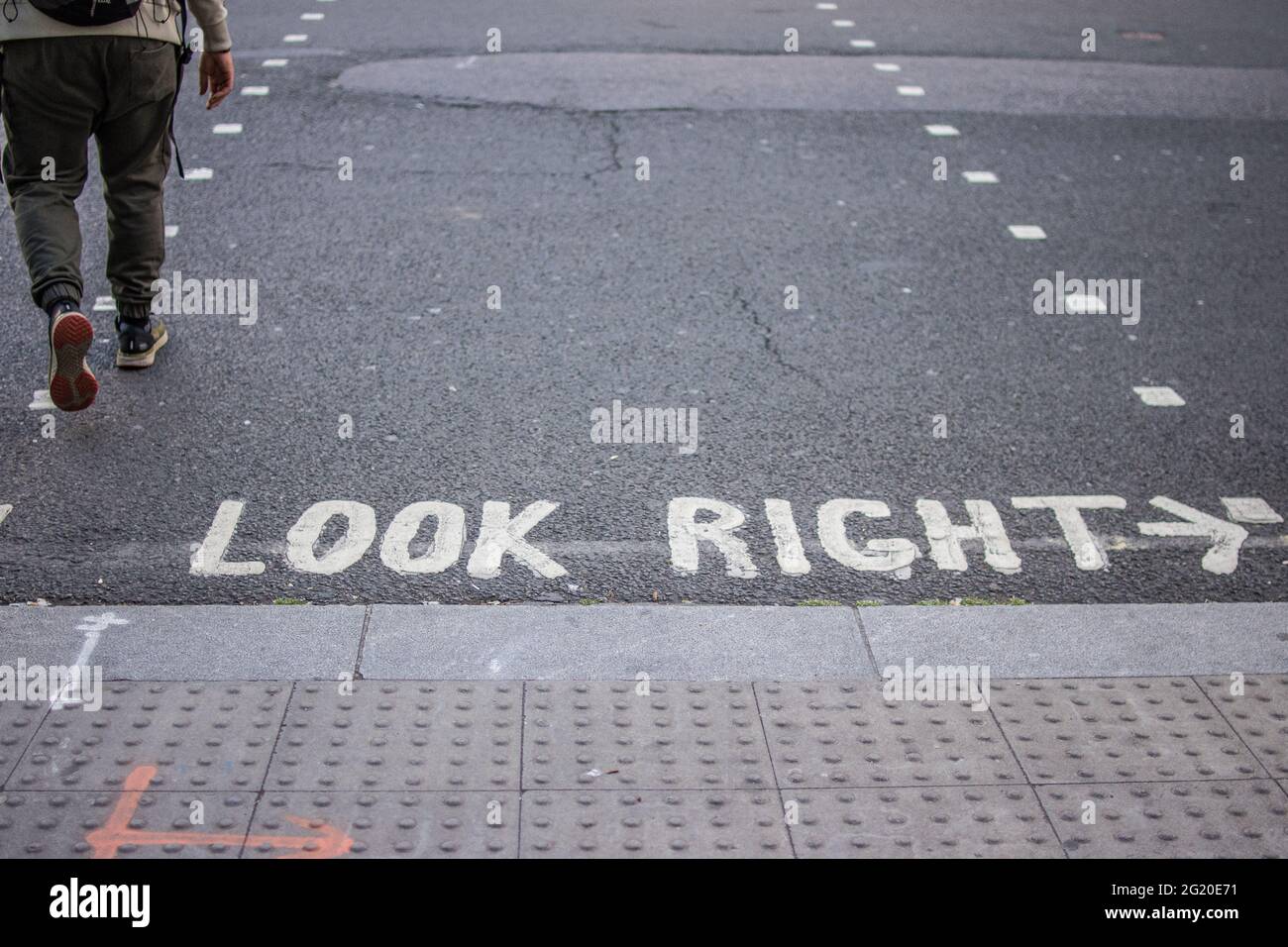 Man walking next to writing on the asphalt reading 'Look Right' in the ...