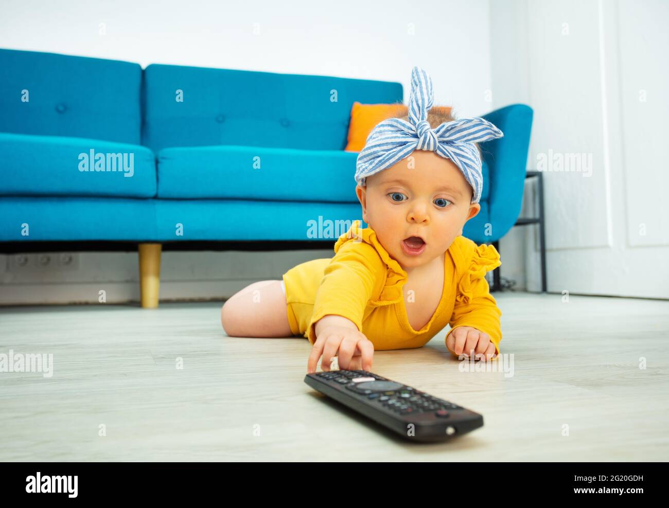 Little baby girl stretch hand reaching tv control Stock Photo - Alamy