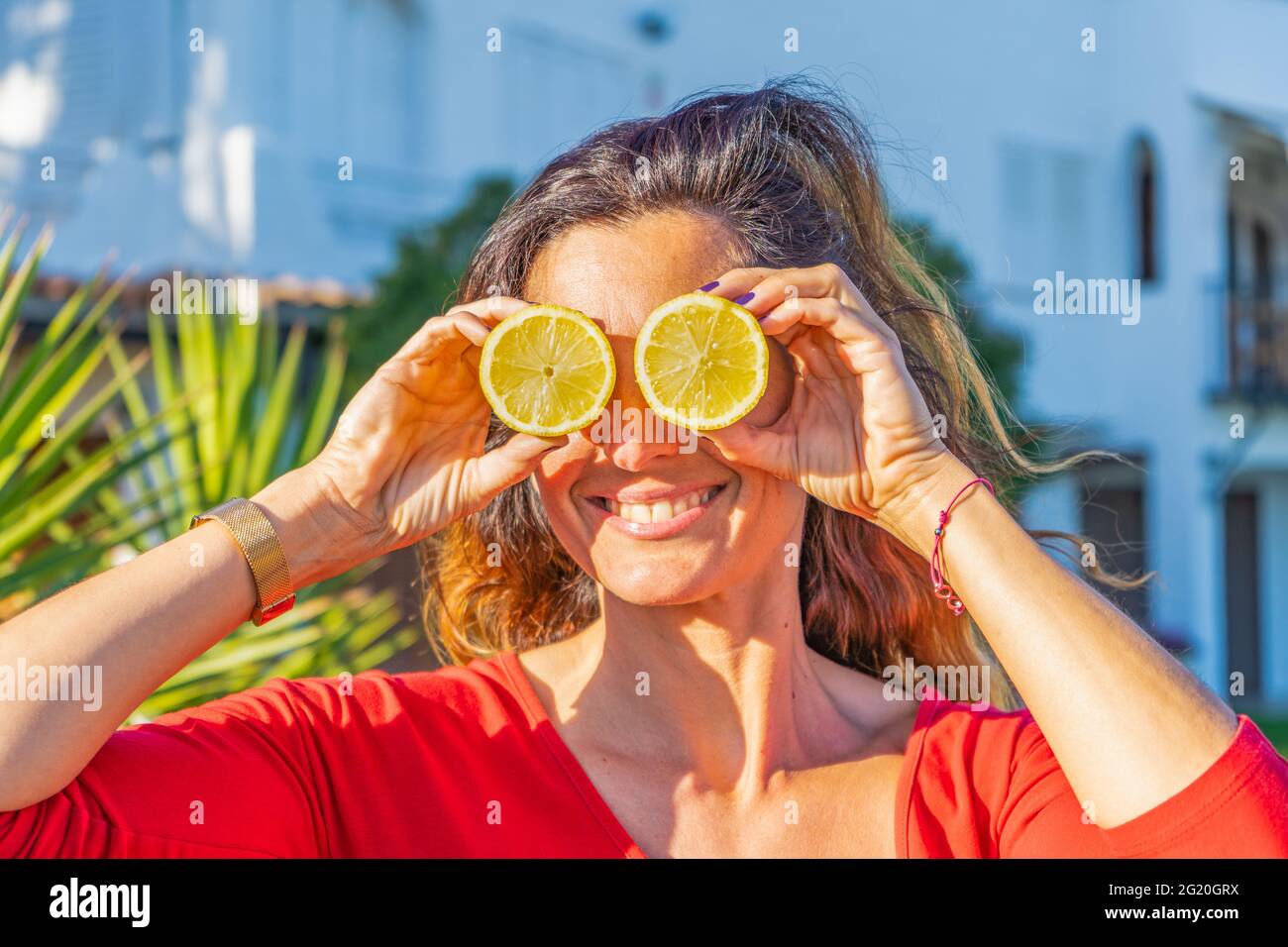 Happy woman holding lemons in front of eyes outdoor.Healthy food ...