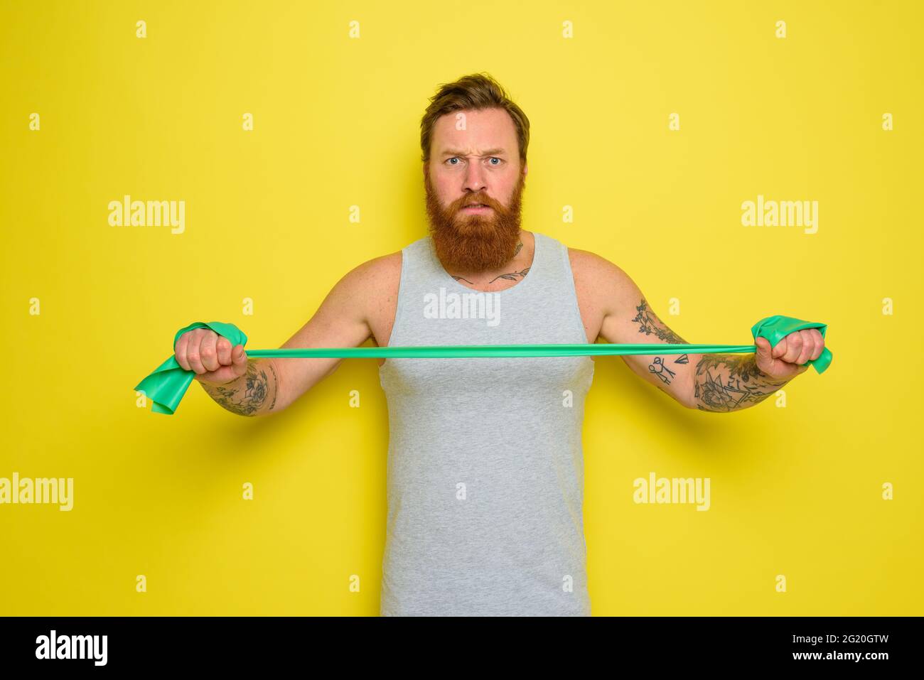 Man with beard and tattoos trains with a rubber band Stock Photo - Alamy