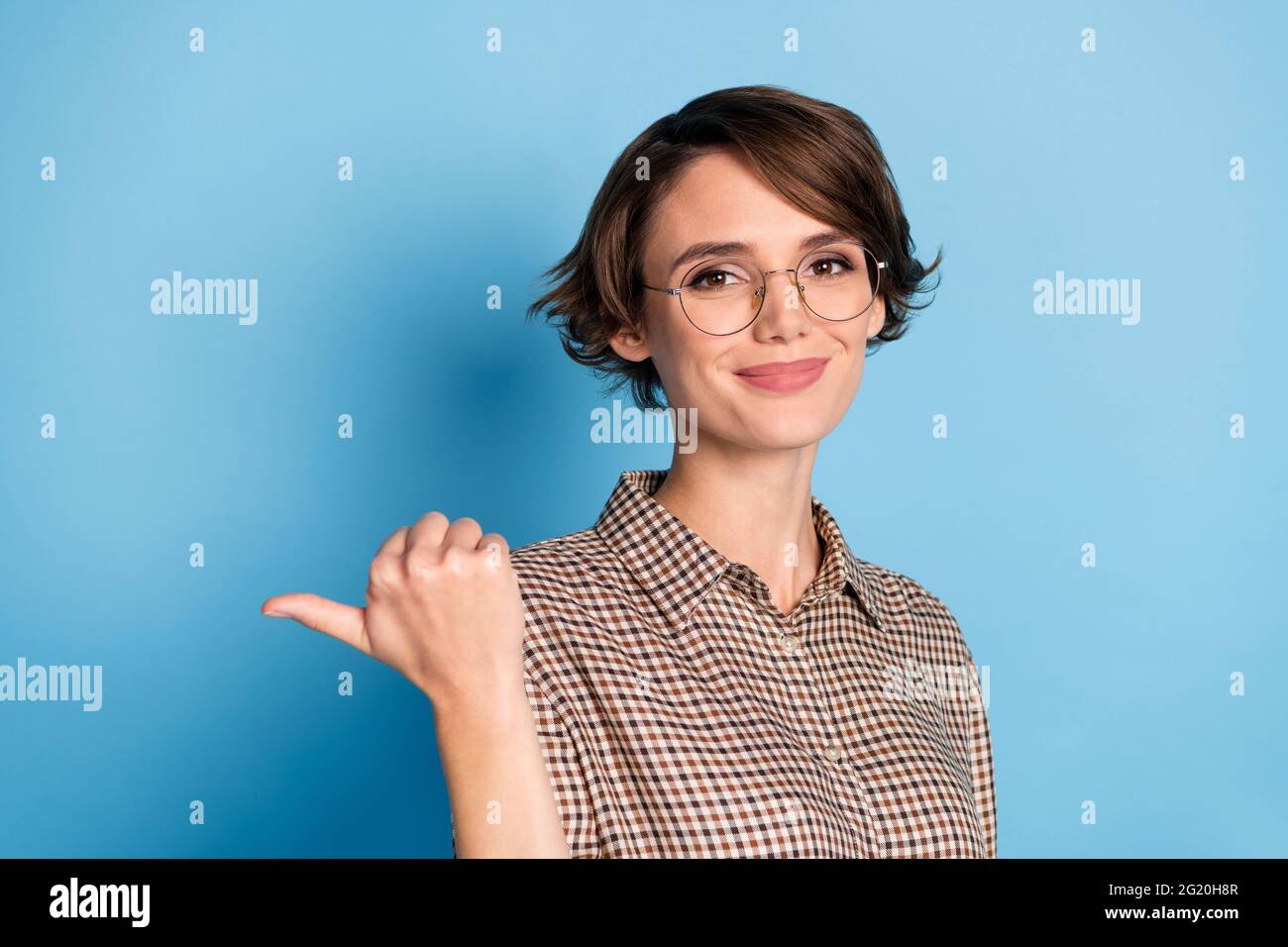 Photo of charming young lady point finger thumb stand empty space wear ...