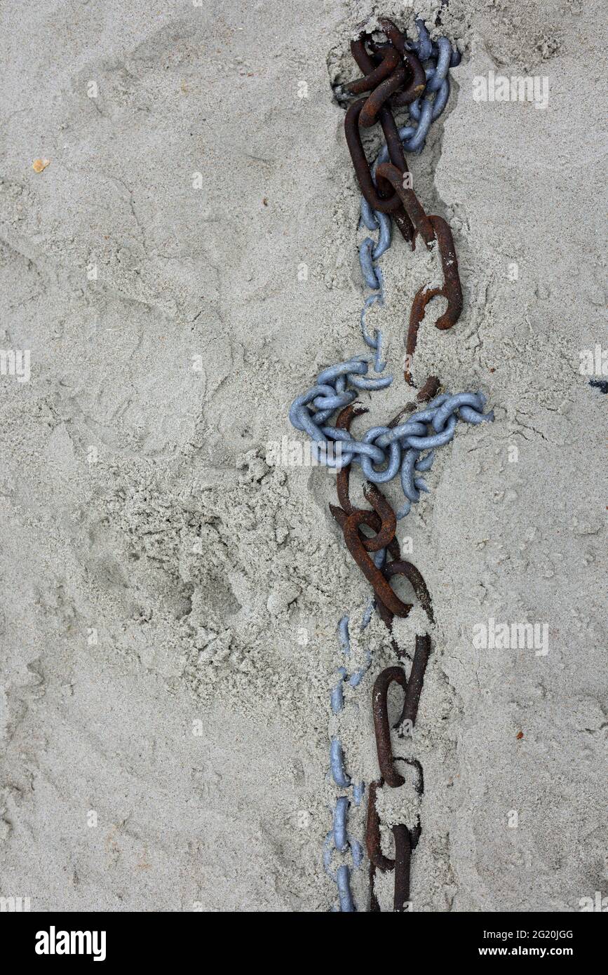 Metal chain seen in beach sand Stock Photo - Alamy
