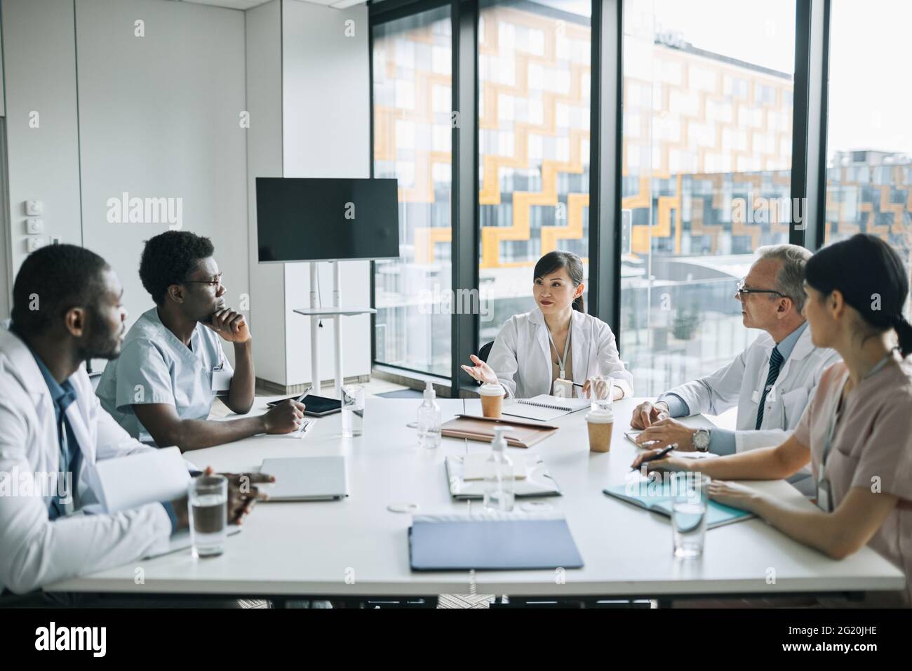 Wide angle view at diverse group of doctors sitting at meeting table in ...