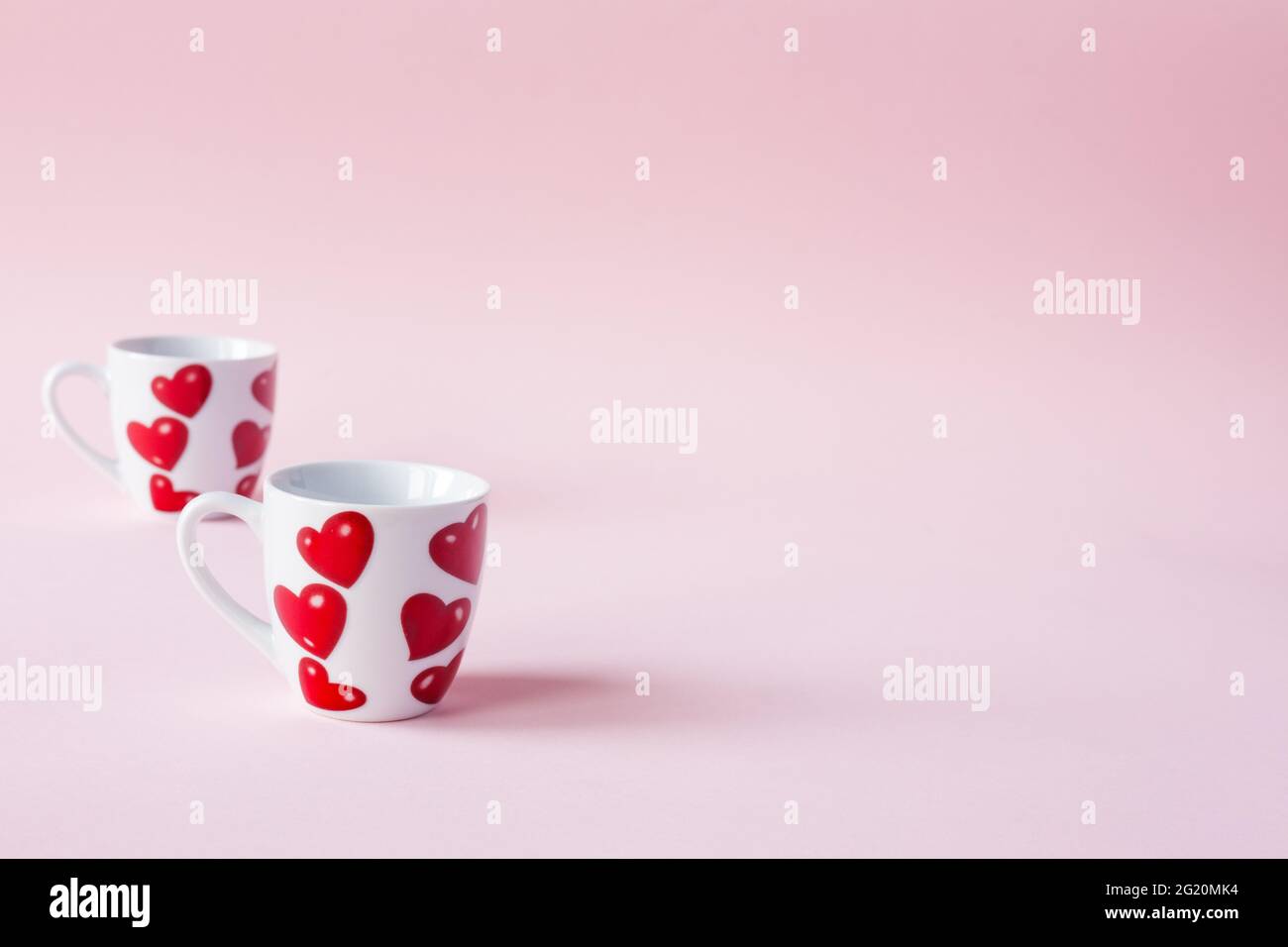 Two cute cups with hearts, shiny bright background, decorative layout ...