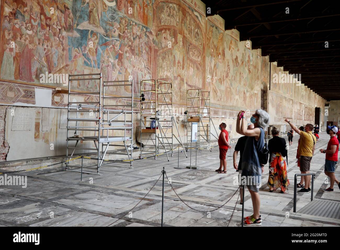 Tourists admire the Medioeval frescoes inside Camposanto Monumentale ...