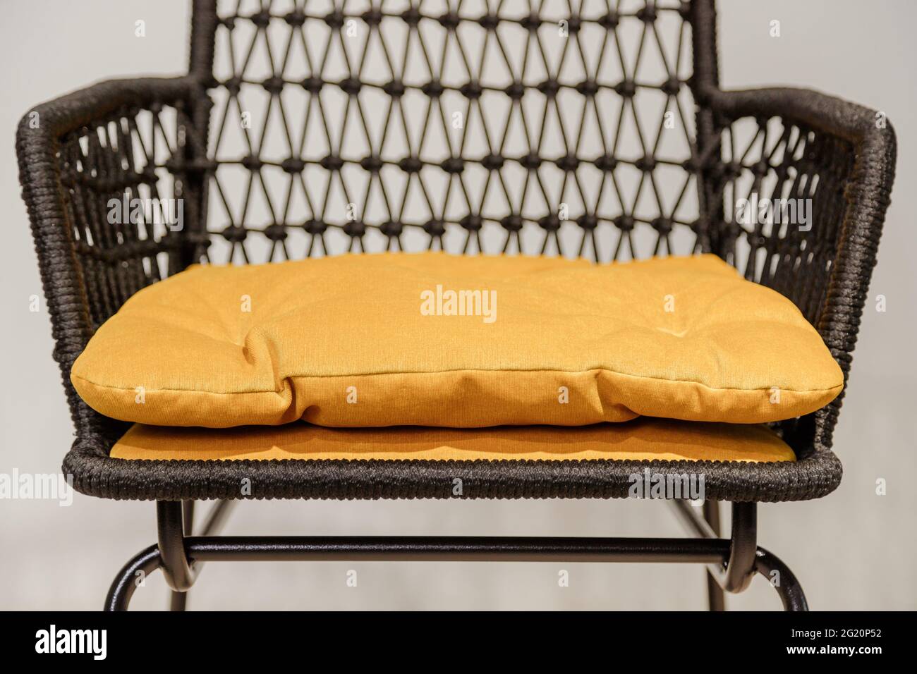 Black wicker chair with yellow pillows. Details Stock Photo - Alamy