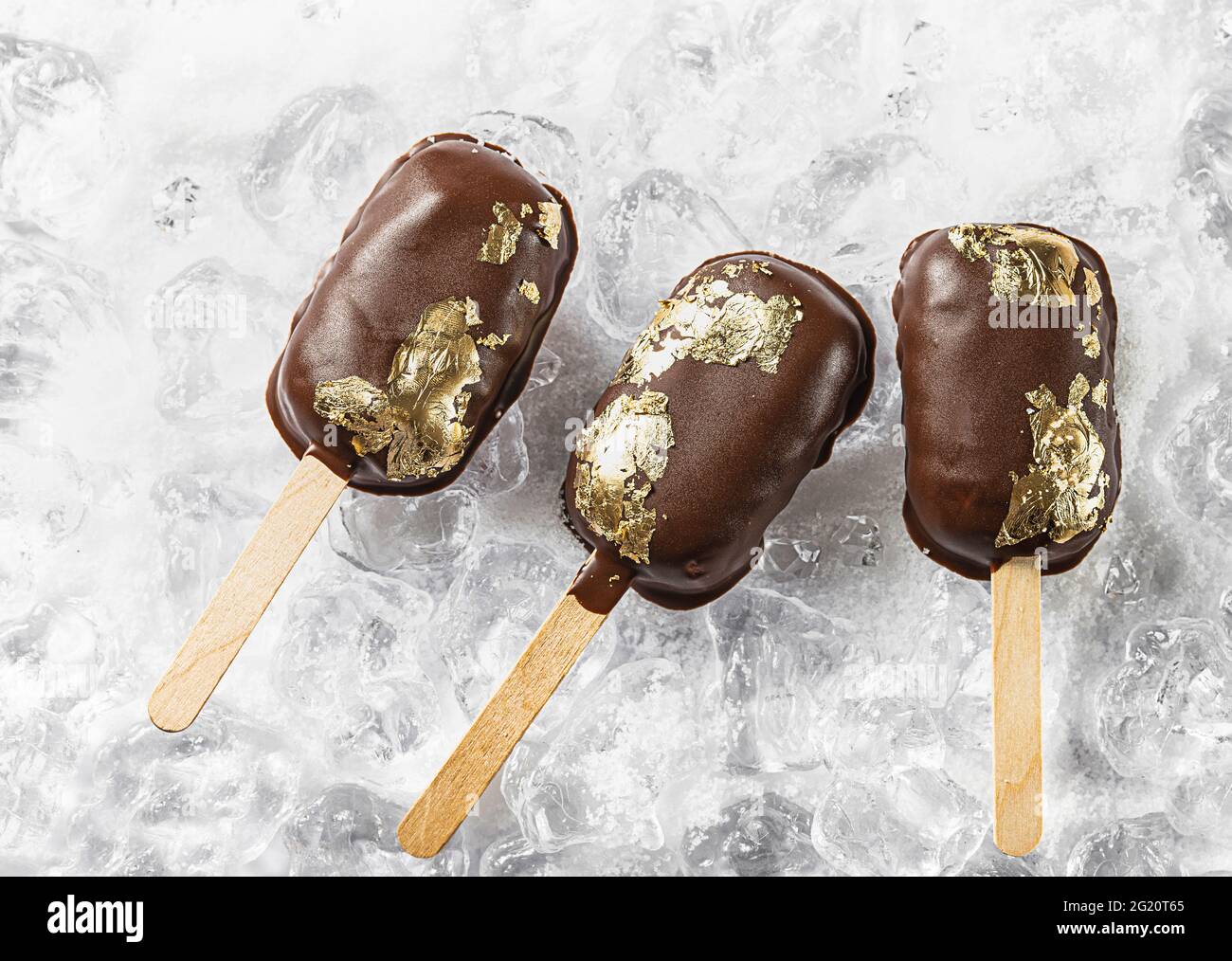 Popsicles, covered with chocolate, with a leaf of edible gold on top on ...
