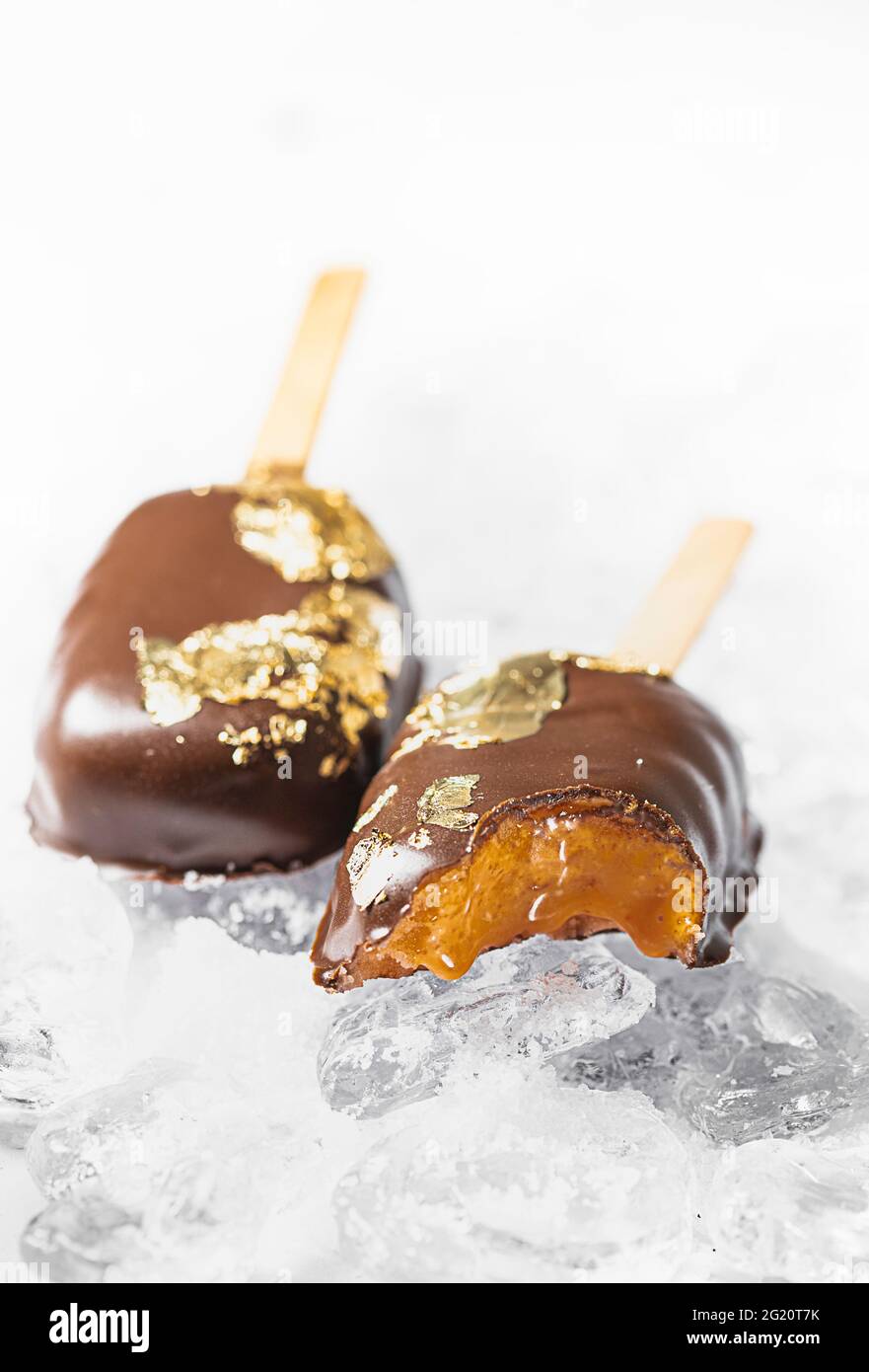 Popsicles, covered with chocolate, with a leaf of edible gold on top on ...