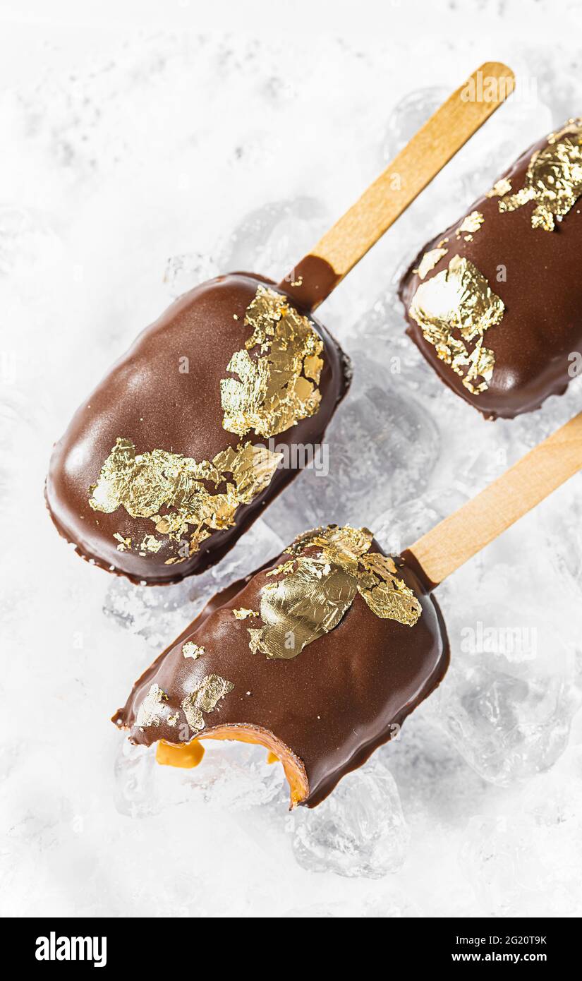 Popsicles, covered with chocolate, with a leaf of edible gold on top on ...