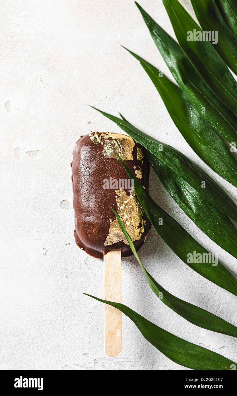 Popsicles, covered with chocolate, with a leaf of edible gold on top on ...