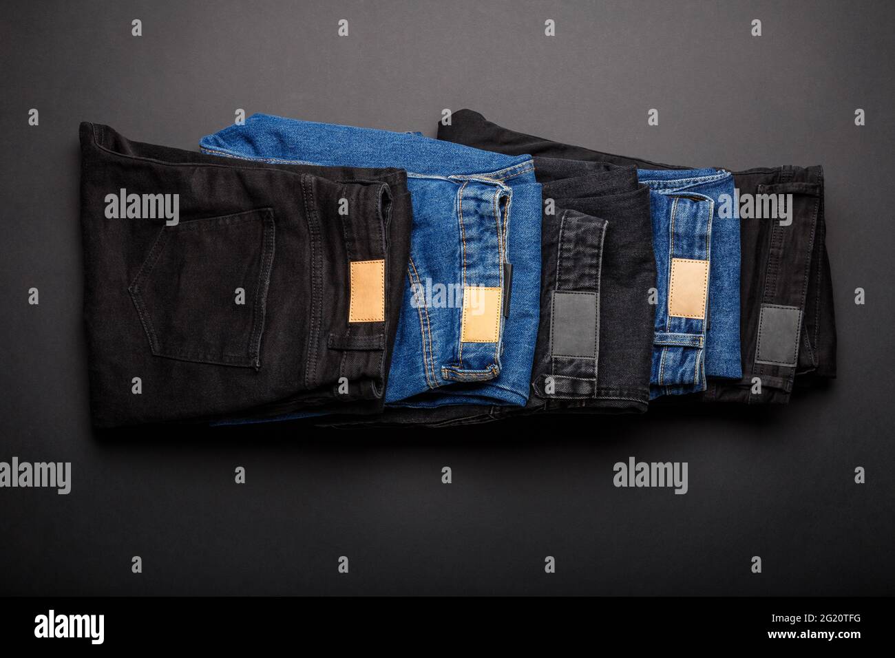 Denim blue jeans and black jean stacked in pile on black background Top ...
